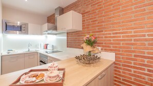 Cozinha moderna com parede de tijolos, eletrodomésticos de aço inoxidável e bancada de madeira com uma bandeja de doces.