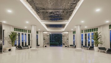 Um hall amplo com piso lustroso, colunas imponentes e áreas de estar.