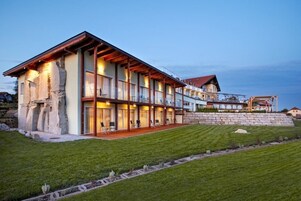 Uma casa moderna de dois andares, com fachada de pedra, janelas grandes e gramado bem cuidado.