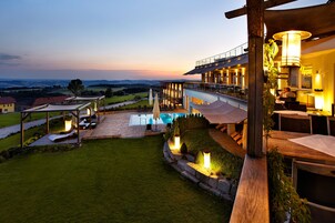 Hotel com piscina, área de estar externa e vista para o campo.