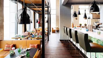 Um restaurante com cabines, mesas altas e um espaço de bar.