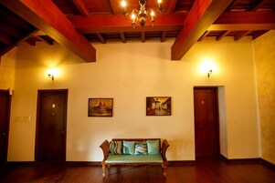 Um quarto com um banco de madeira, duas portas e duas luminárias fixadas na parede.