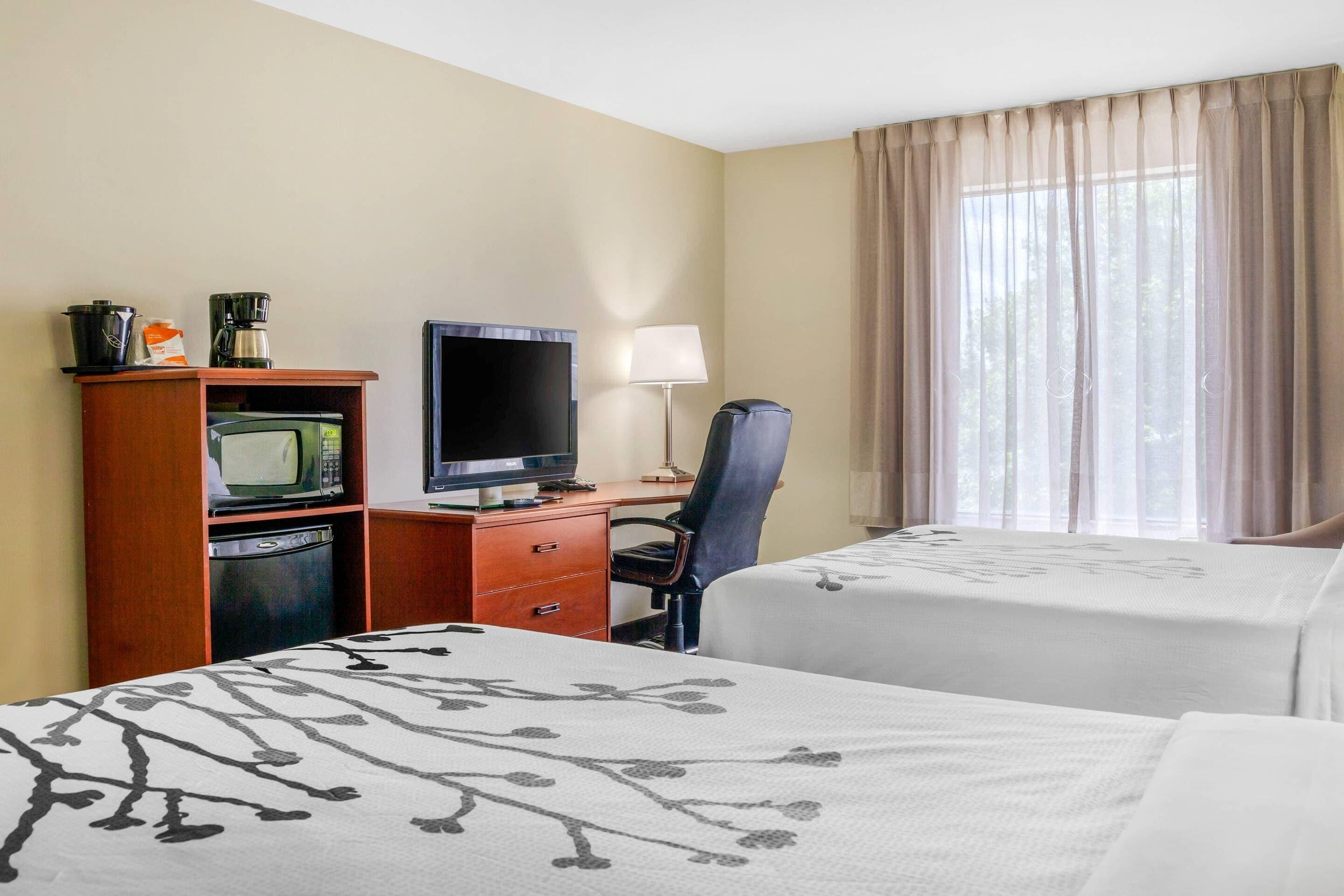 Quarto de hotel com duas camas, uma mesa de trabalho, televisão, micro-ondas e máquina de café.