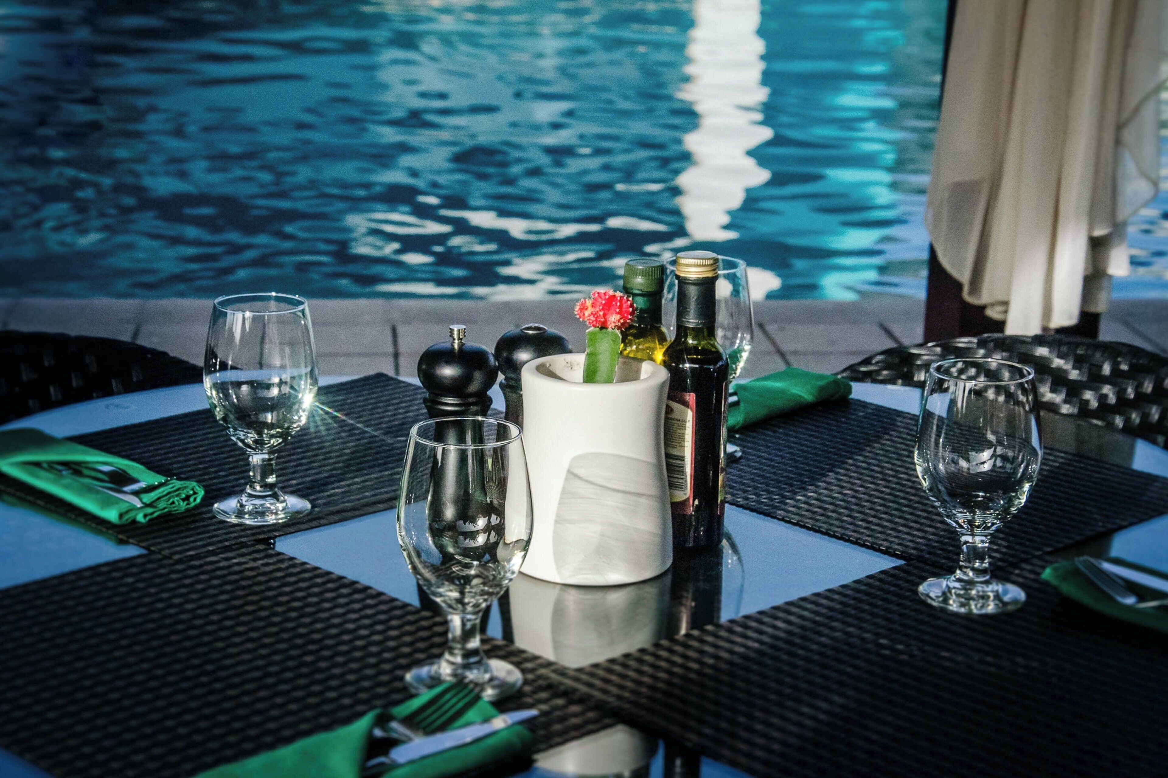 Mesa posta para refeição com vista para uma piscina.