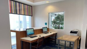 Espaço de escritório moderno com duas mesas, cada uma com um computador e teclado, e uma impressora à direita.
