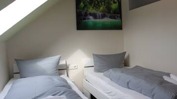 Quarto com duas camas de solteiro, um claraboia e um quadro de uma cascata.