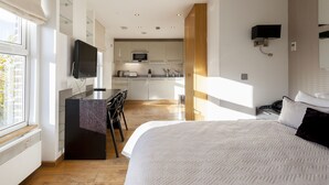 Quarto de hotel moderno com uma cama grande, uma escrivaninha com uma TV de tela plana, um micro-ondas e vista para a cozinha.