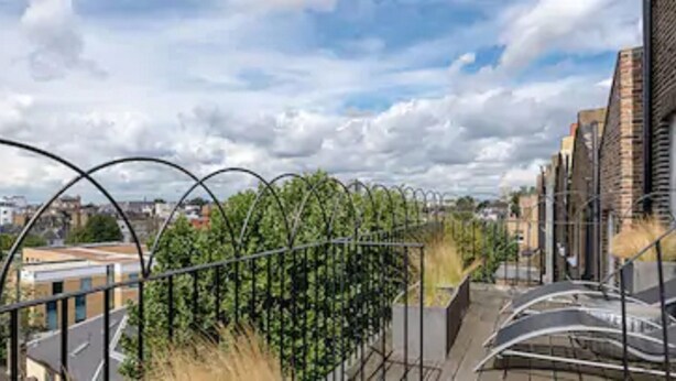 Visão de um horizonte urbano com edifícios, uma rua e uma cerca de metal.