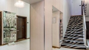 Um corredor com escadaria em padrão de zebra, uma porta e uma escultura de vidro decorativa.