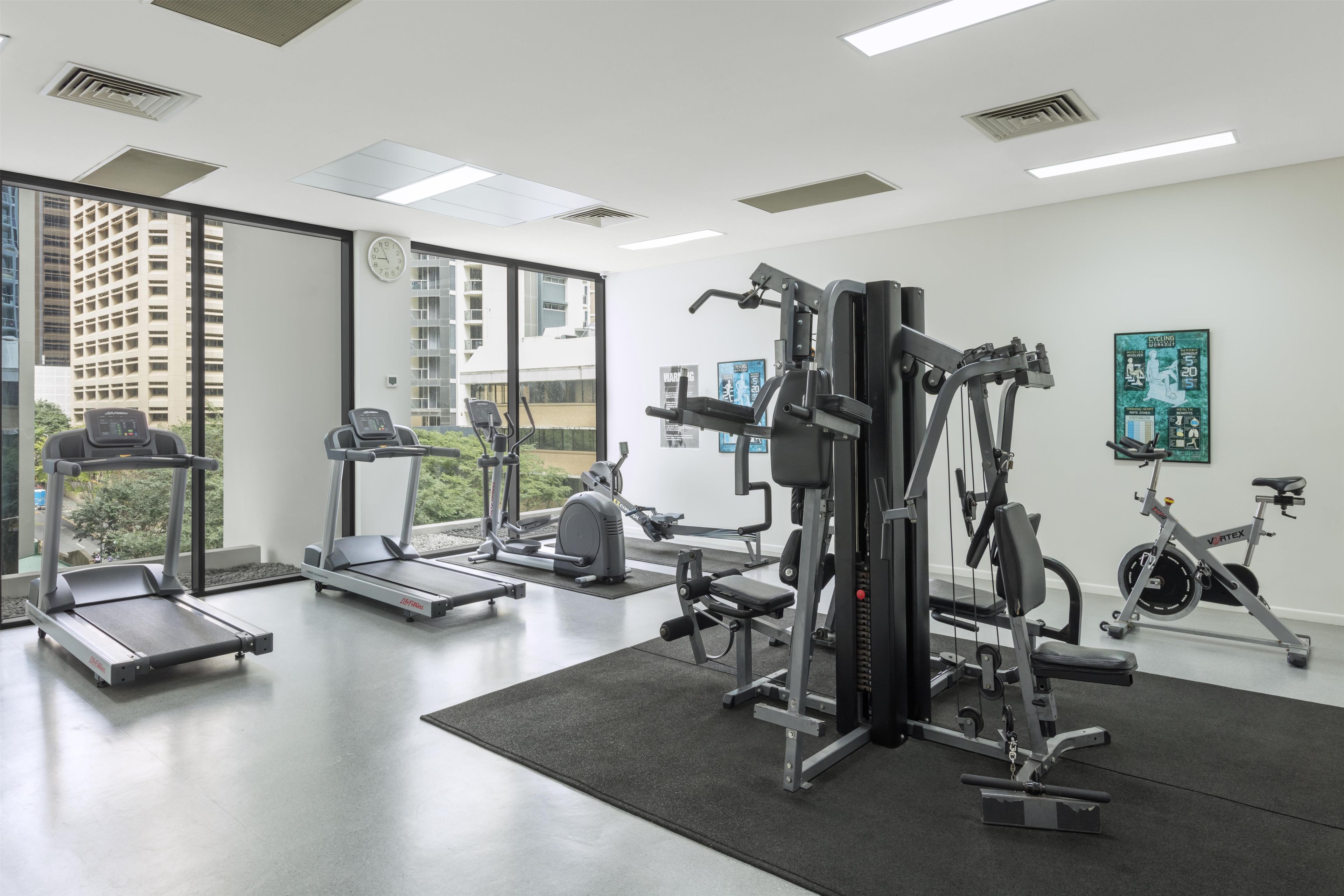 Academia com esteiras, equipamentos de musculação e bicicletas.