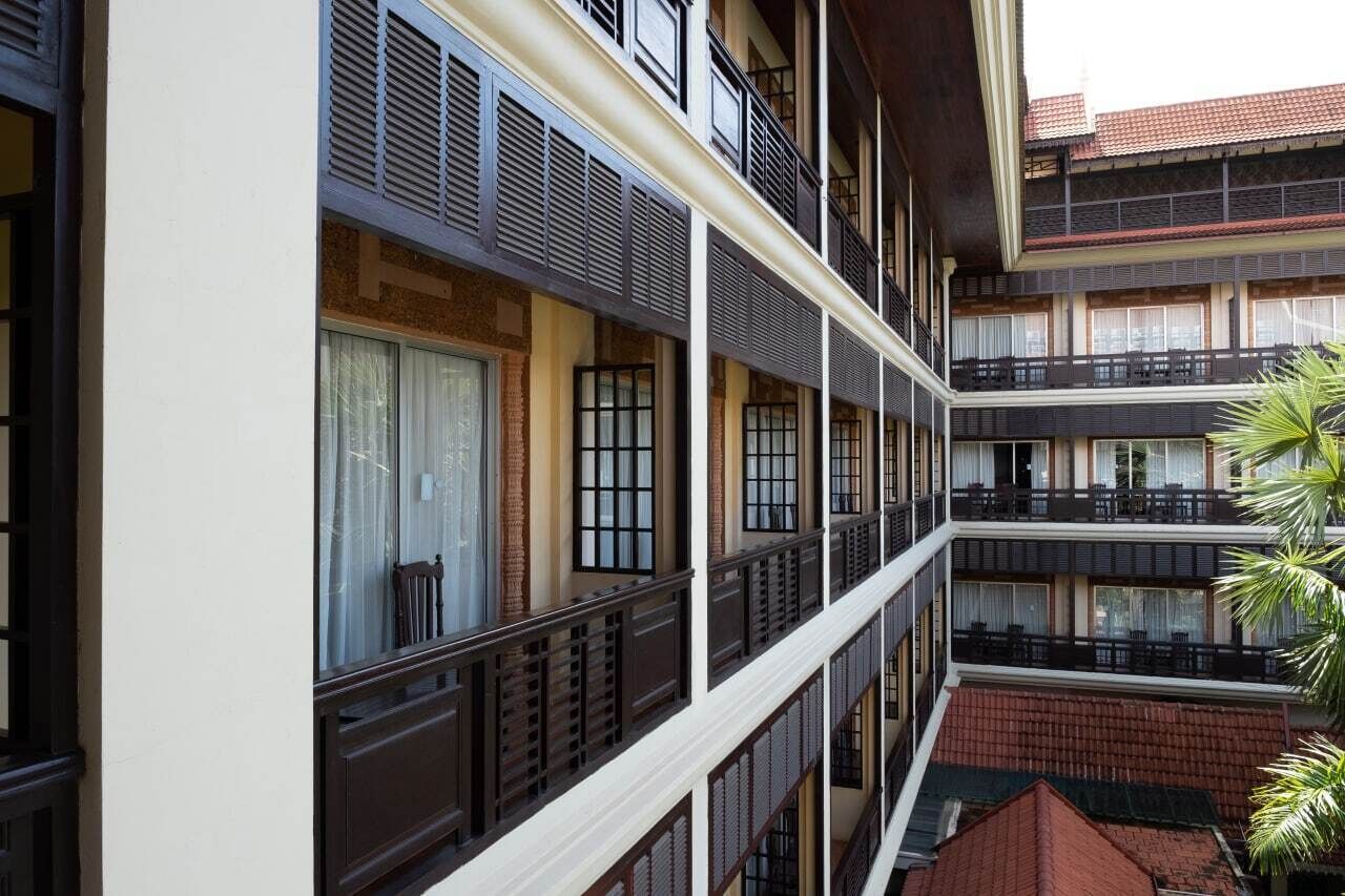 Um hotel com vários andares, varandas, janelas amplas e fachada de tijolos.
