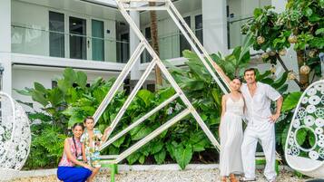 Um edifício moderno com estrutura de vidro geométrica, vegetação exuberante e esquema de cores branco e verde.