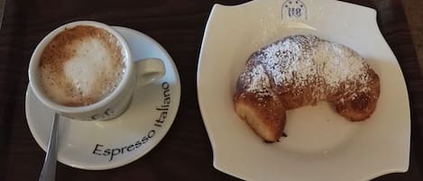 Uma bandeja com uma xícara de café expresso e um doce em cima de uma mesa.