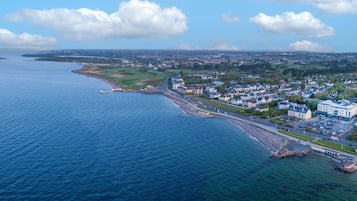 Vista aérea de uma vila costeira com um porto de iates, edifícios residenciais e um campo de golfe.