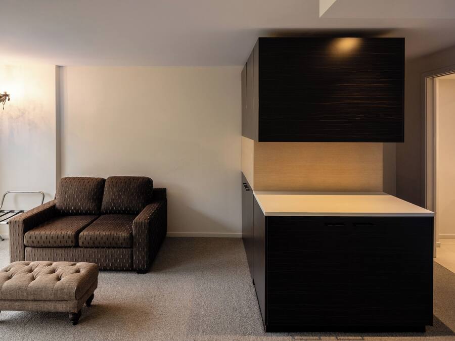 Uma sala de estar moderna com sofá, banquinho e um armário embutido preto.