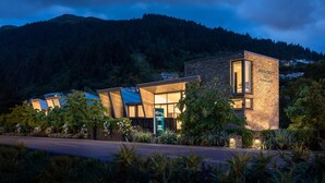 Um hotel com fachada de pedra, grandes janelas e uma placa que diz "Queenstown Park Boutique Hotel".