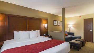 Quarto de hotel com uma cama grande, uma escrivaninha, uma cadeira e um sofá.