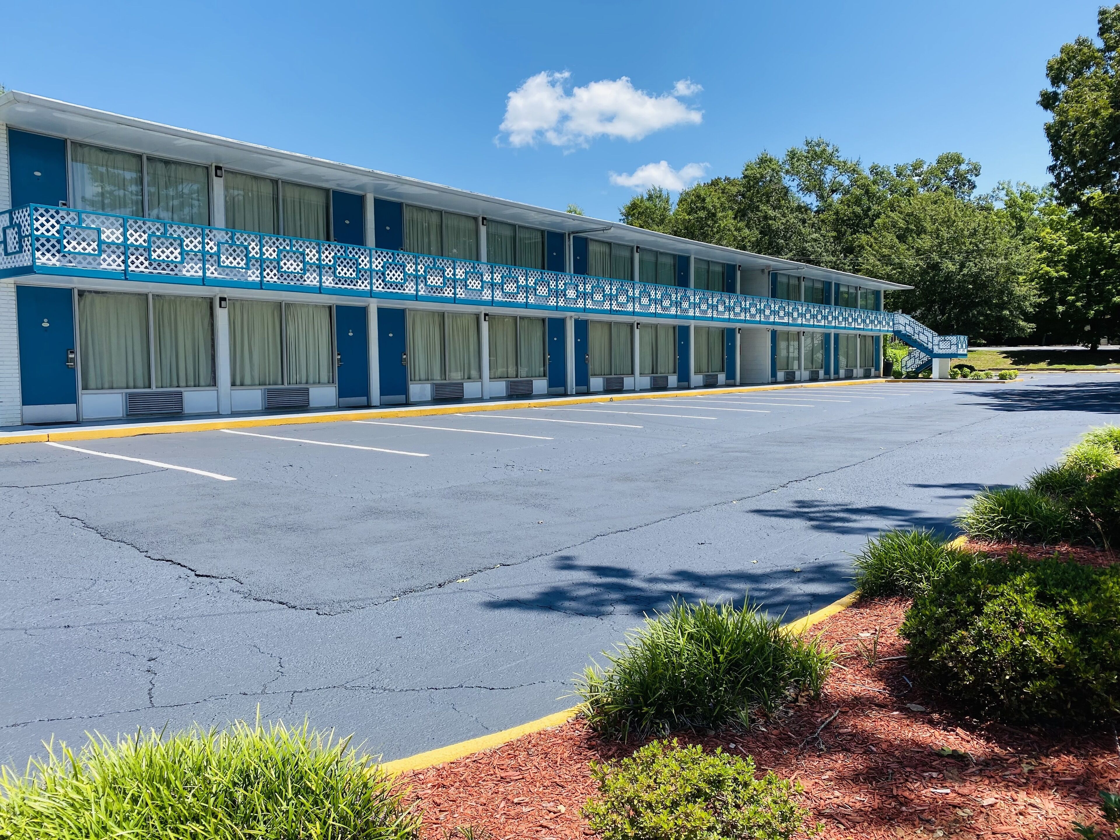 Um motel com fachada azul, várias divisões e uma galeria coberta.