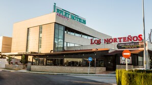 Um edifício de hotel moderno com uma placa que diz 'Los Nortenos' e 'Carnes y Pescados a la Brasa'.