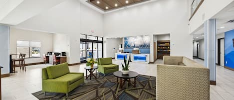 Um lobby amplo com áreas de estar, balcão de recepção e vista para a paisagem urbana.