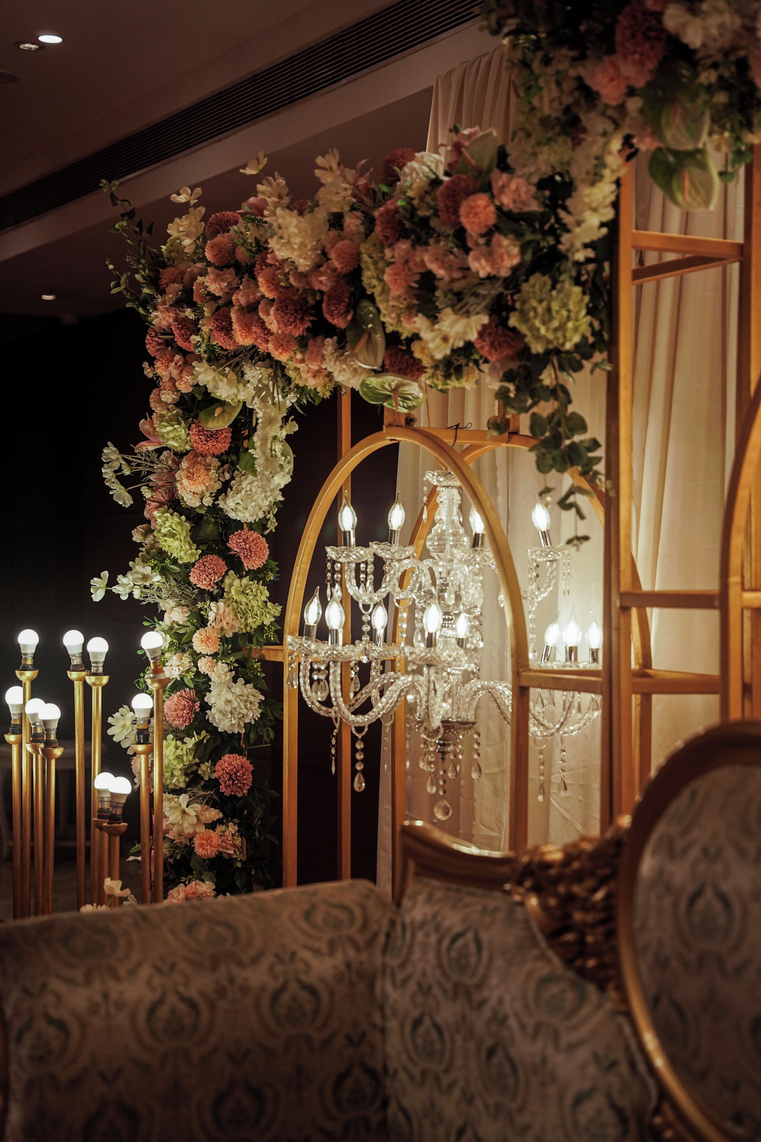 Um quarto com um arco floral, um candelabro e um espelho.