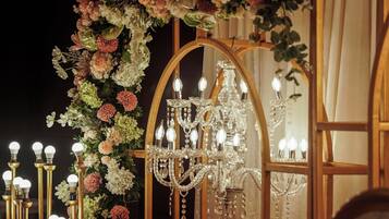 Um quarto com um arco floral, um candelabro e um espelho.