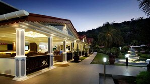 Um saguão de hotel com balcão de recepção, área de estar e um elemento decorativo com água.