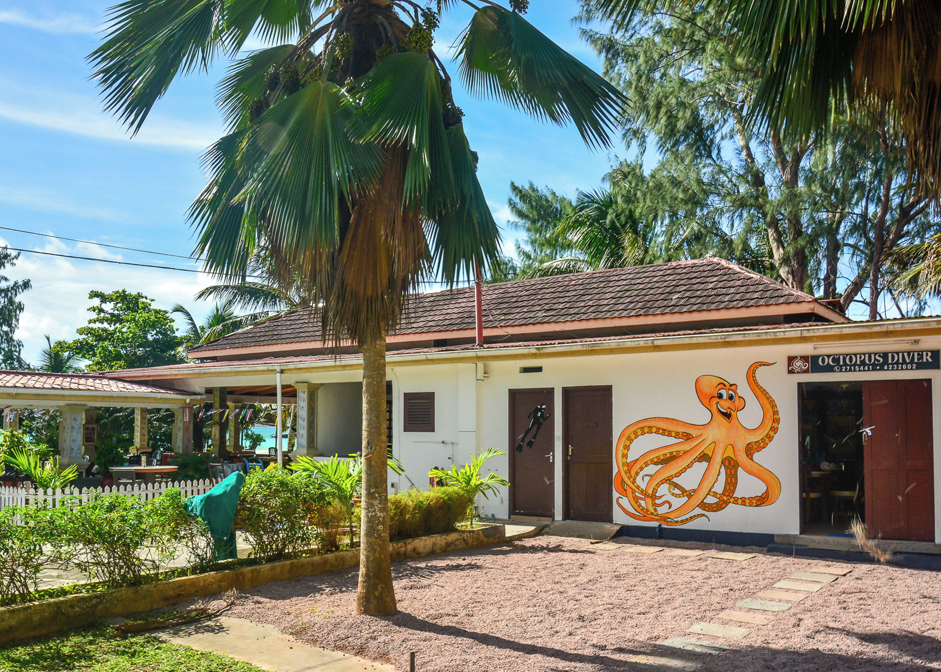 Um edifício com um mural de polvo, telhado de azulejos e cerca branca.