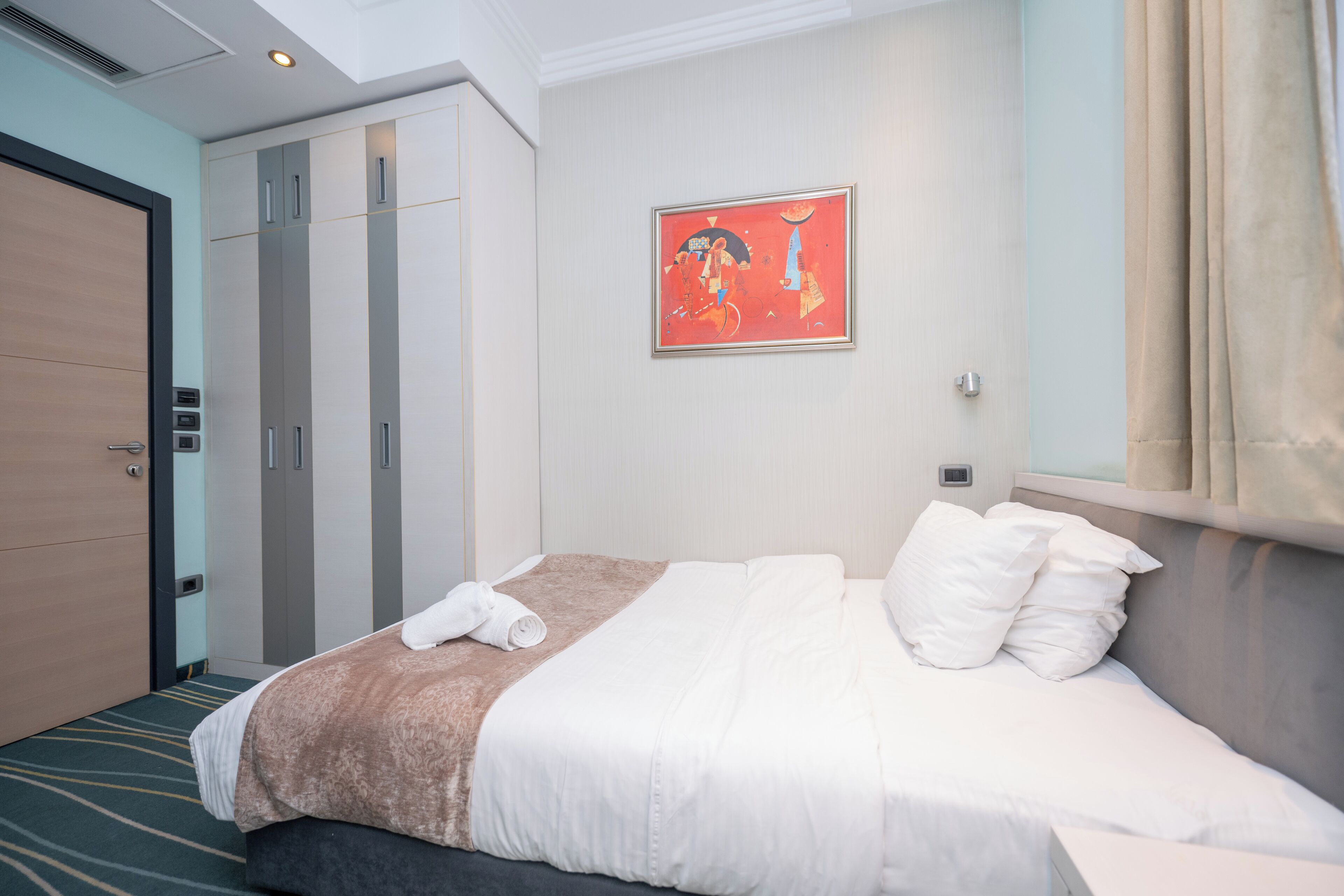 Quarto de hotel com cama, um quadro na parede e um guarda-roupa.