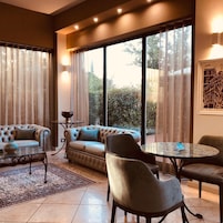 Uma sala de estar moderna com sofá, poltronas, mesa de centro e vista através de grandes janelas.