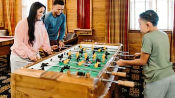 Uma mesa de futebol de madeira num espaço com paredes de madeira e um tapete estampado.