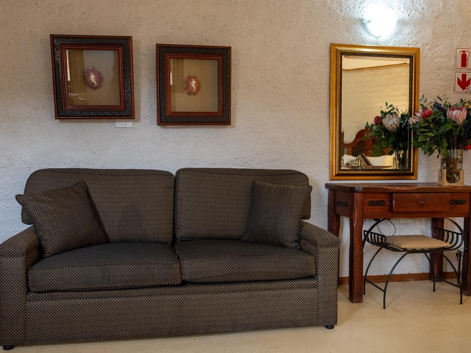 Uma sala de estar com um sofá estampado, uma mesinha de madeira com espelho e duas quadros na parede.