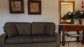 Uma sala de estar com um sofá estampado, uma mesinha de madeira com espelho e duas quadros na parede.