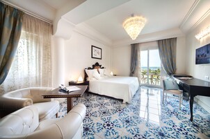 Quarto de hotel com cama, escrivaninha, cadeira e varanda com vista.