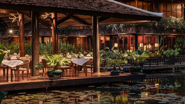 Restaurante com área externa, lago com nenúfares e uma cascata.
