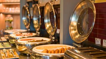 Disposição de buffet com vários recipientes de comida e utensílios de servir.
