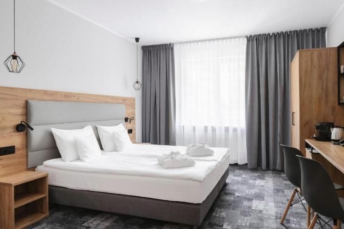 Quarto de hotel moderno com cama, escrivaninha e guarda-roupa.