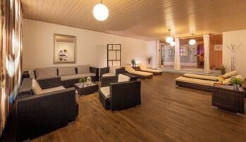 Uma área de estar moderna com mobiliário de vime, divisória de vidro e banheiro com chuveiro à vista.