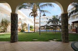 Pátio com piscina, palmeiras e área de estar coberta.