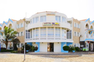 Hotel com fachada curva, várias varandas e placa com a inscrição 'Rent a Car'.