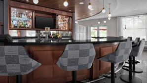 Uma área de bar moderna com balcão curvo, vários banquinhos e uma variedade de garrafas de bebidas.
