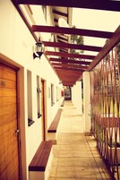 Corredor com bancos de madeira, corrimão de metal e porta de madeira com o número 106.