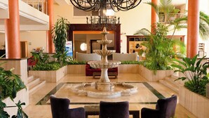 Um lobby com uma fonte central, área de estar e várias plantas.