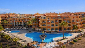Resort com várias piscinas, espreguiçadeiras e palmeiras.