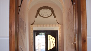Um corredor com teto em arco e porta com painel de vidro decorativo.