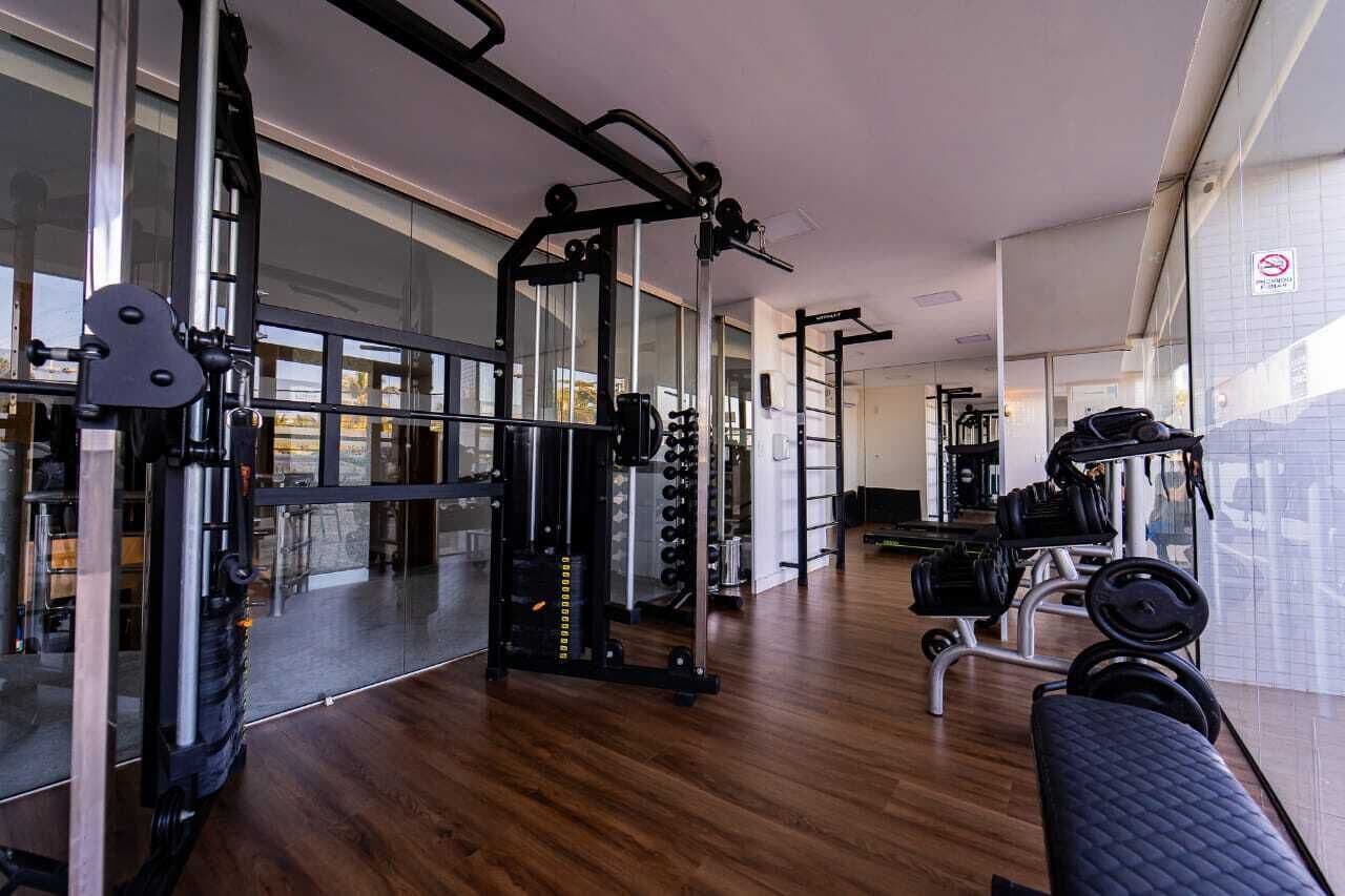 Academia com equipamentos de musculação, um banco e um espelho na parede.