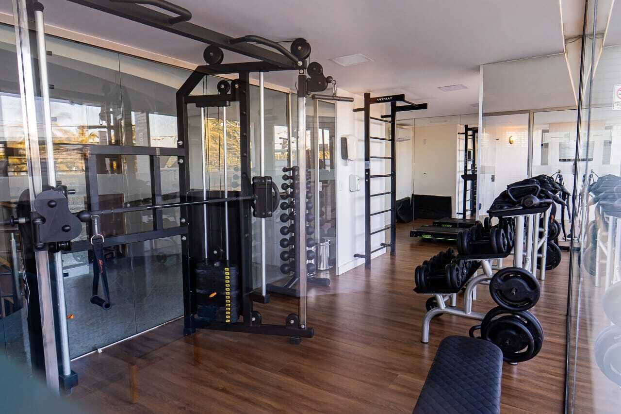 Uma academia com equipamentos de musculação, um banco e um espelho na parede.