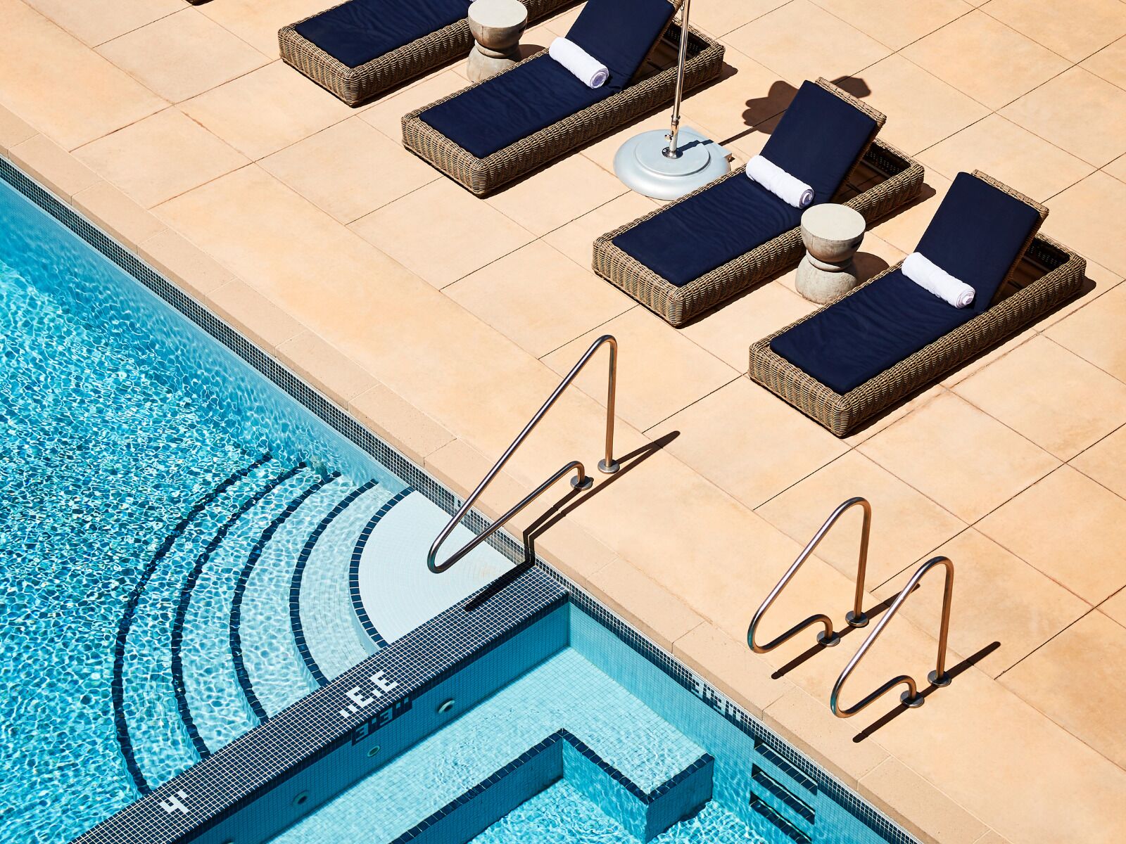 Uma área à beira da piscina com espreguiçadeiras e piscina.