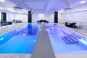 Piscina interior moderna com pistas demarcadas, um corredor central e áreas de estar de ambos os lados.