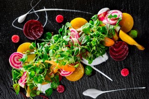 Salada colorida com diversos vegetais e folhas sobre superfície escura.